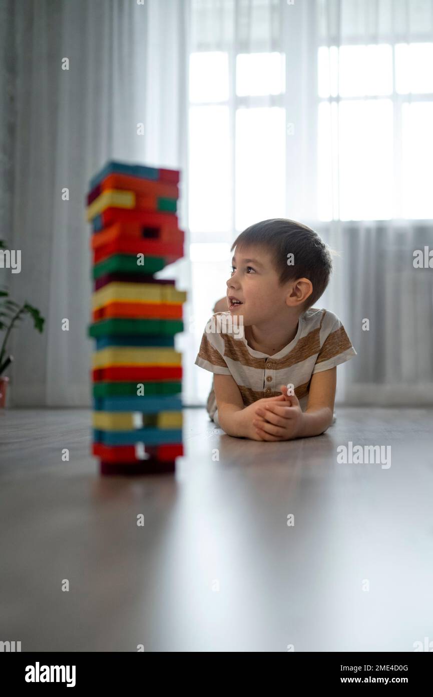 Boy lying on floor with stack of toy blocks at home Stock Photo - Alamy
