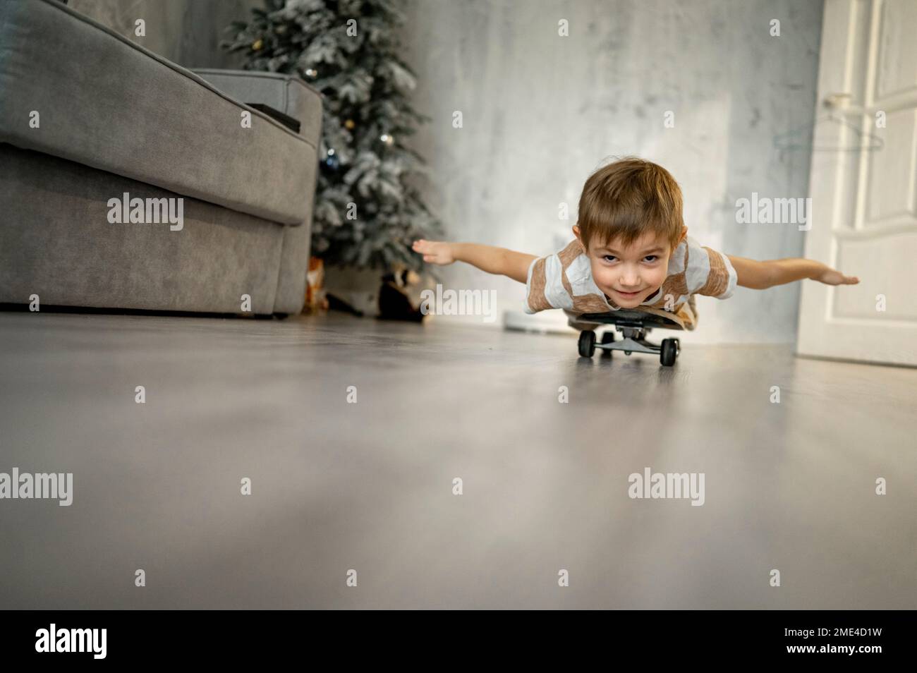 Happy boy with arms outstretched lying on skateboard at home Stock ...