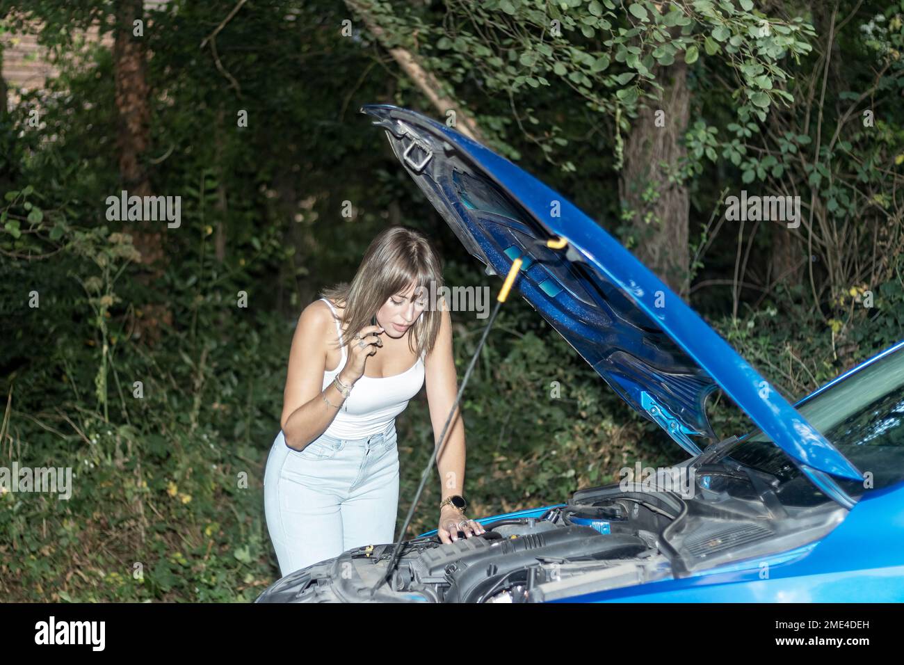 Young woman standing near a parked broken down car having trouble with ...