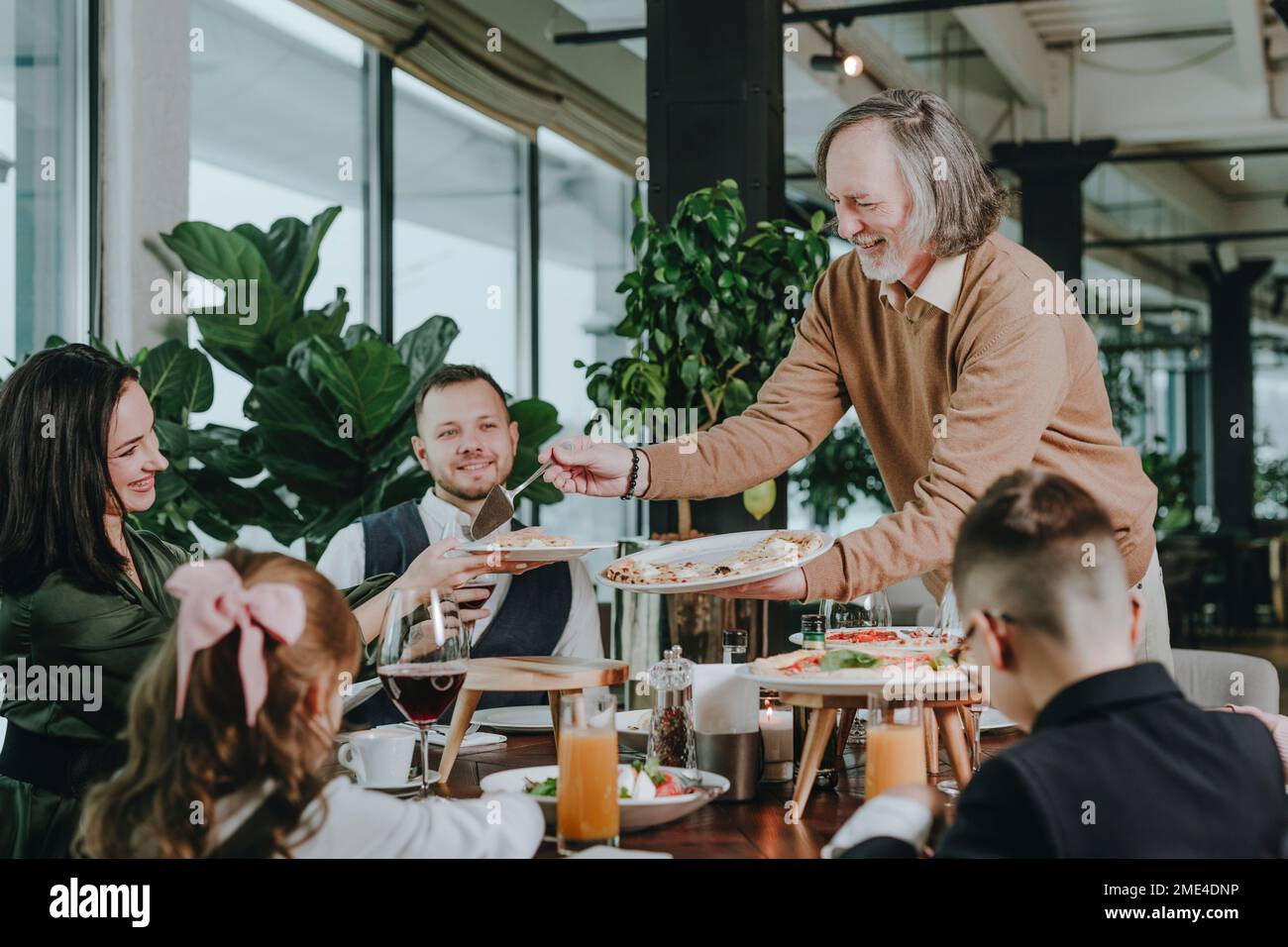 Happy senior man serving food to family at cafe Stock Photo - Alamy