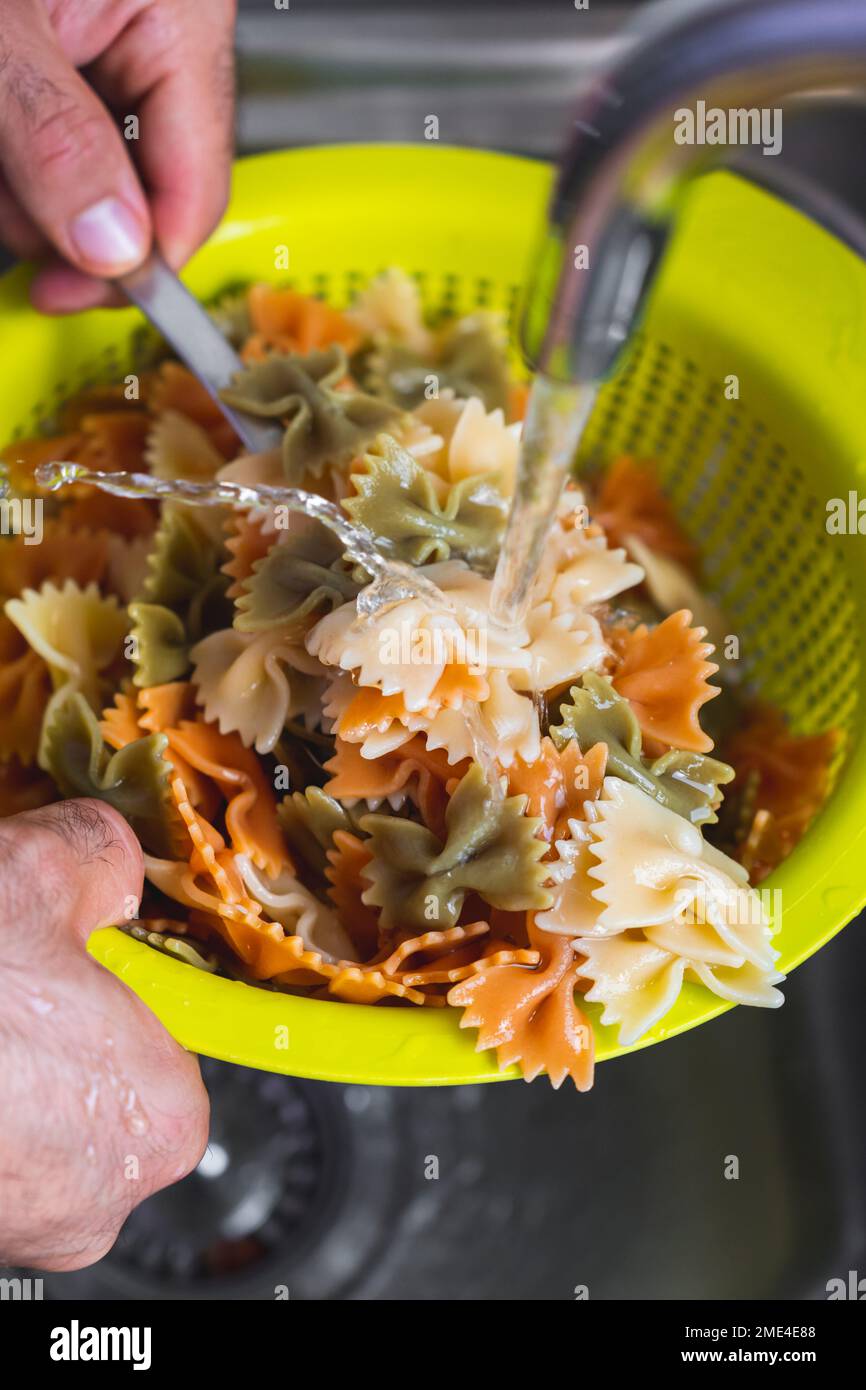 Hands of man washing bow tie pasta in sink Stock Photo - Alamy