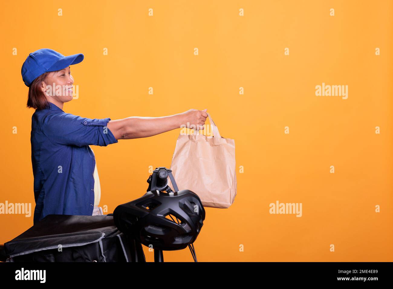Senior takeaway delivery employee delivering takeout food in recycled ...