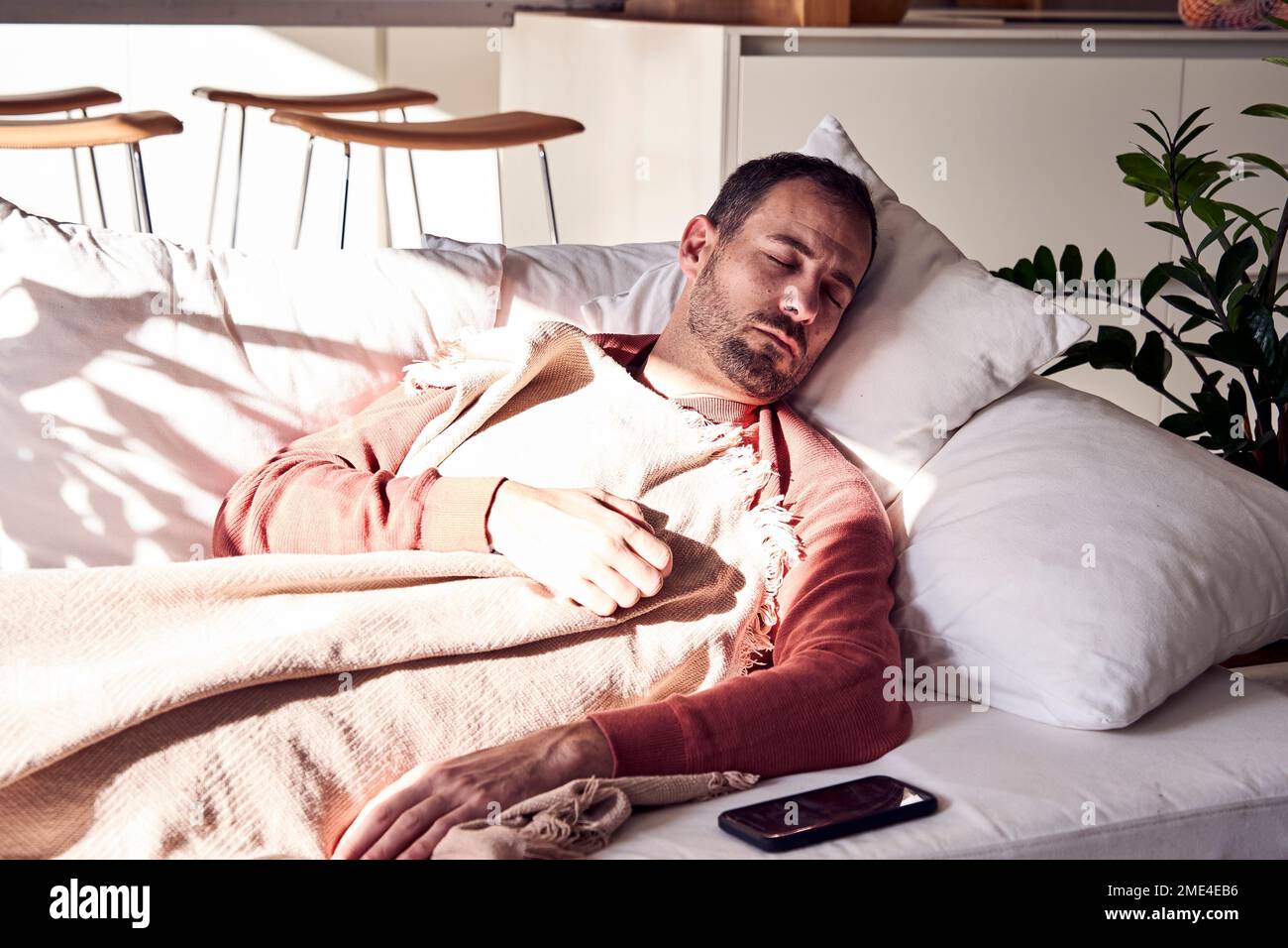 Man sleeping by smart phone on sofa at home Stock Photo - Alamy