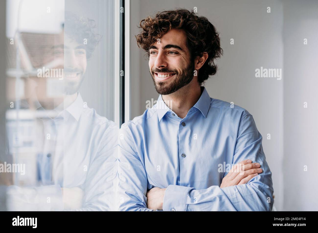 Happy contemplative businessman looking through window in office Stock ...