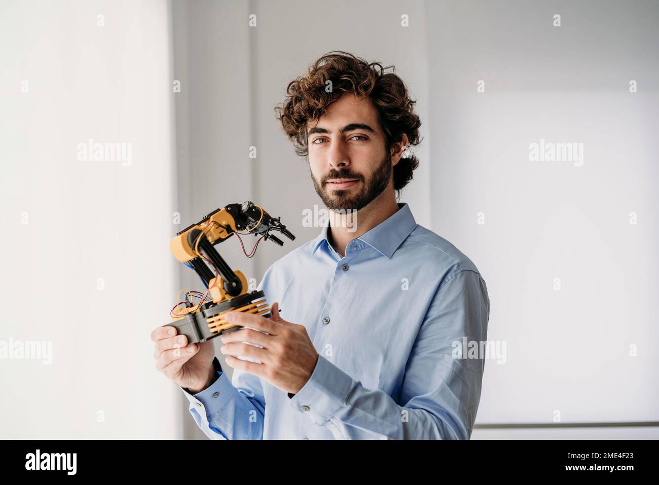 Young businessman holding robotic arm in office Stock Photo - Alamy
