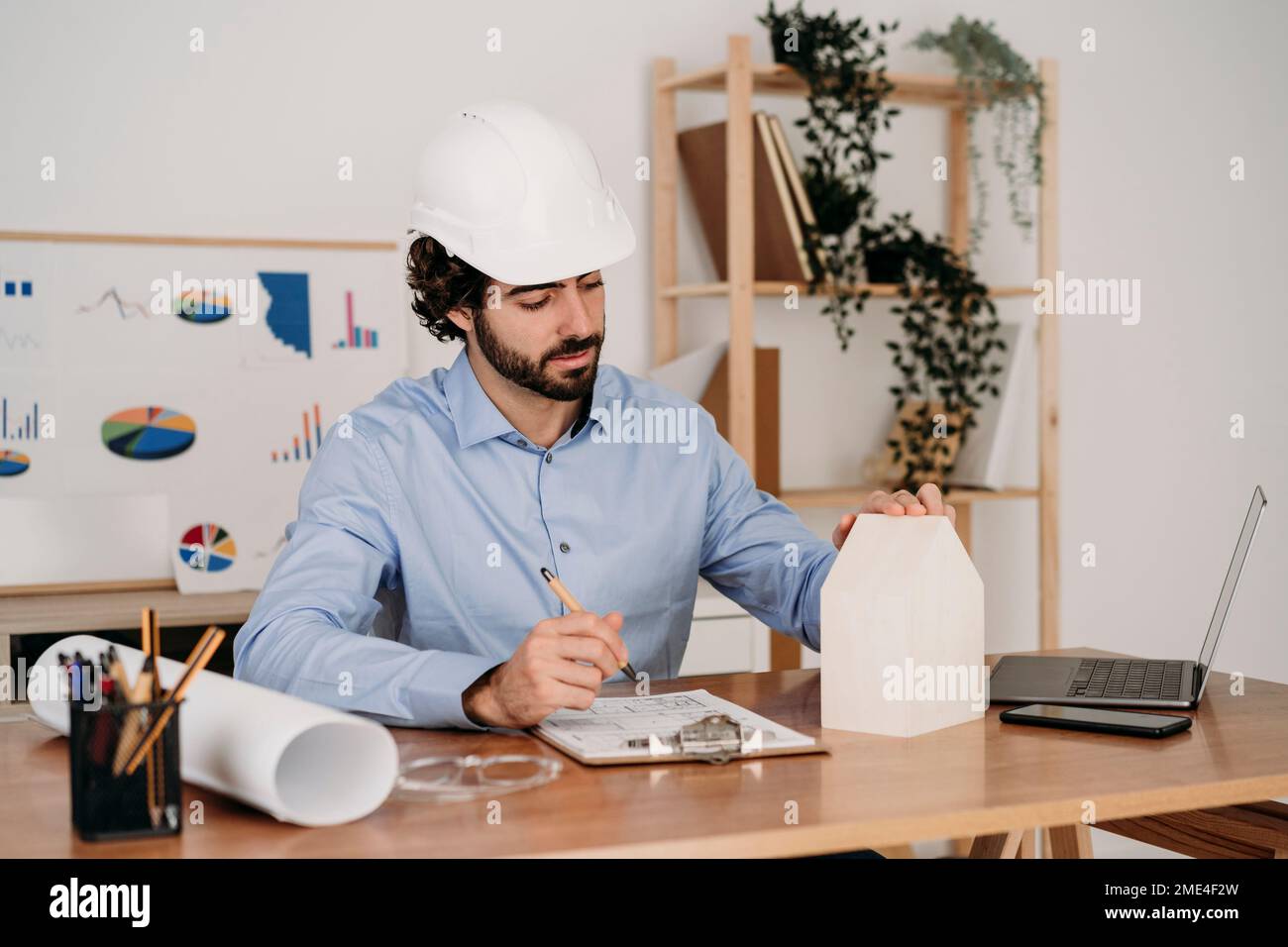Architect working on house model with blueprints in office Stock Photo ...