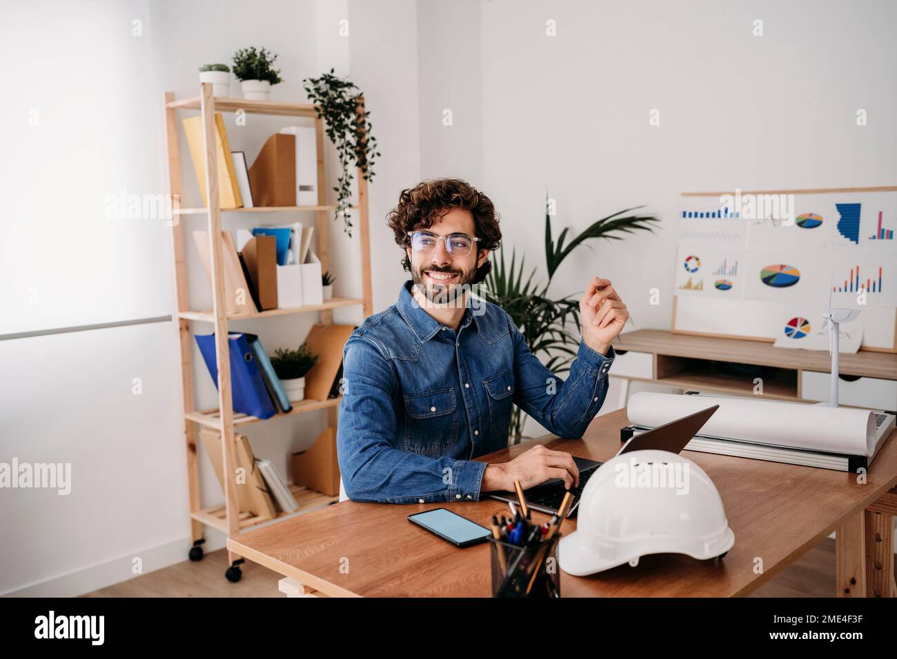 Thoughtful young engineer with laptop on desk in office Stock Photo - Alamy