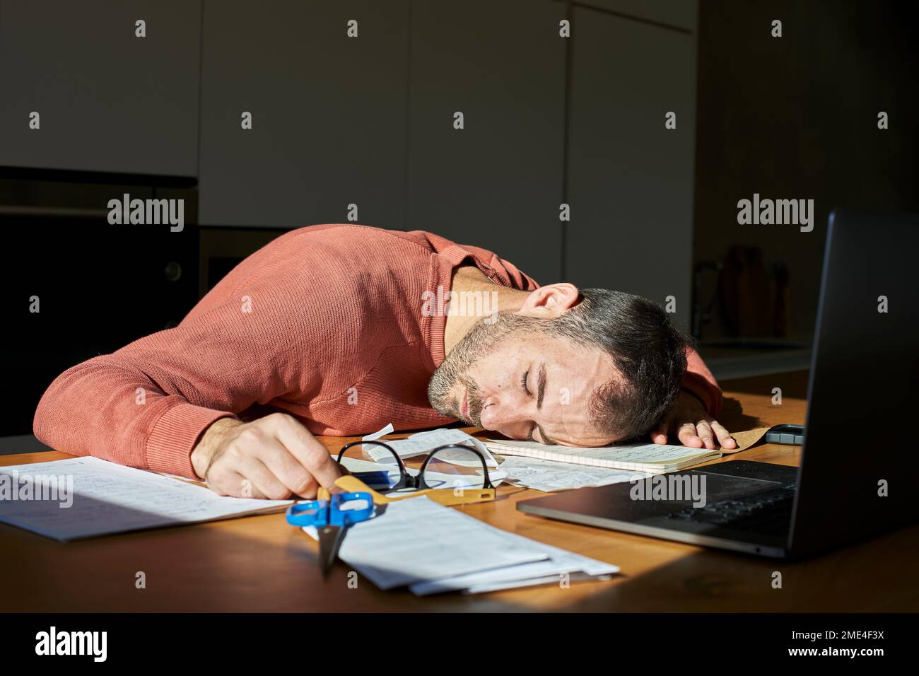 Tired man sleeping on desk with documents and laptop Stock Photo - Alamy