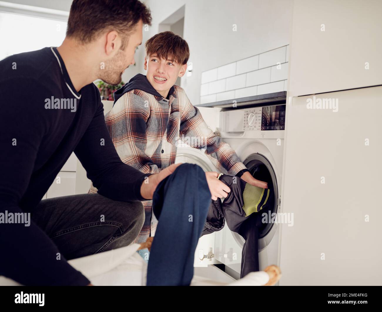Father and son putting laundry into washing machine at home Stock Photo ...
