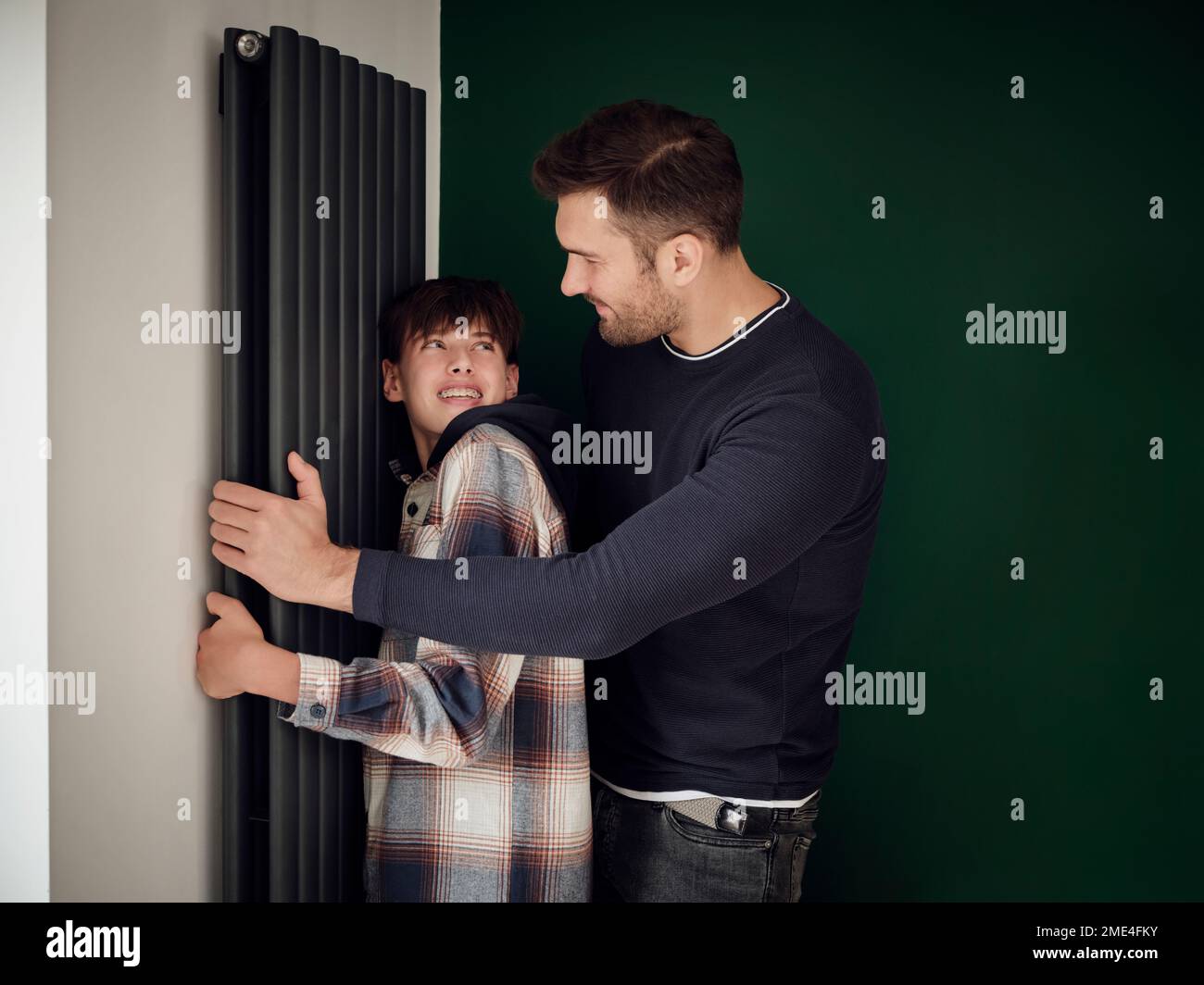 Son and father at home touching and hugging radiator Stock Photo - Alamy