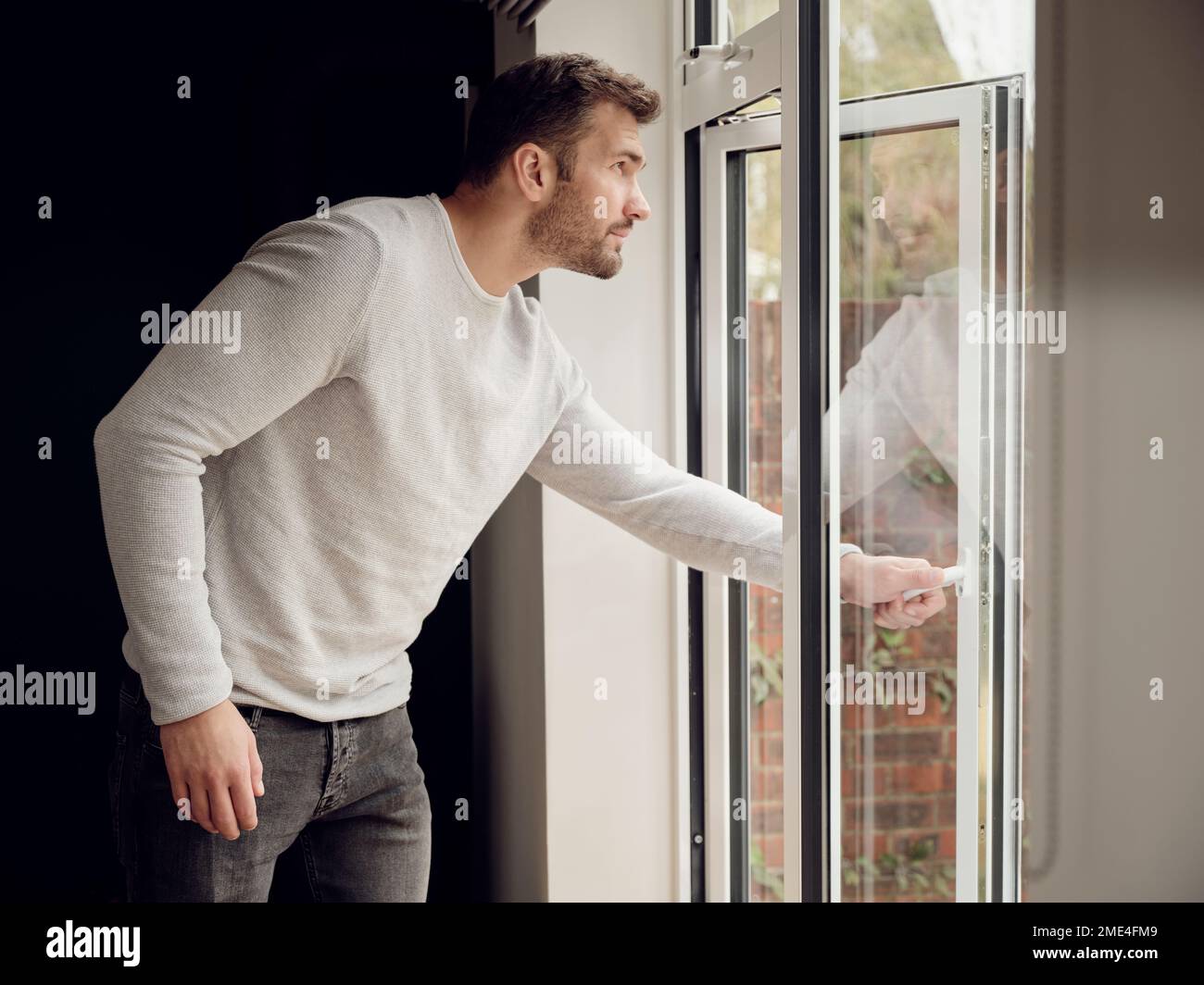 Man looking out and closing the window at home Stock Photo - Alamy