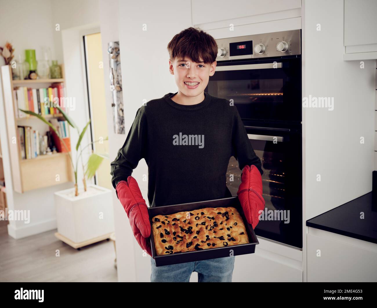 Portrait of boy holding baking tray with fresh focaccia bread in the ...