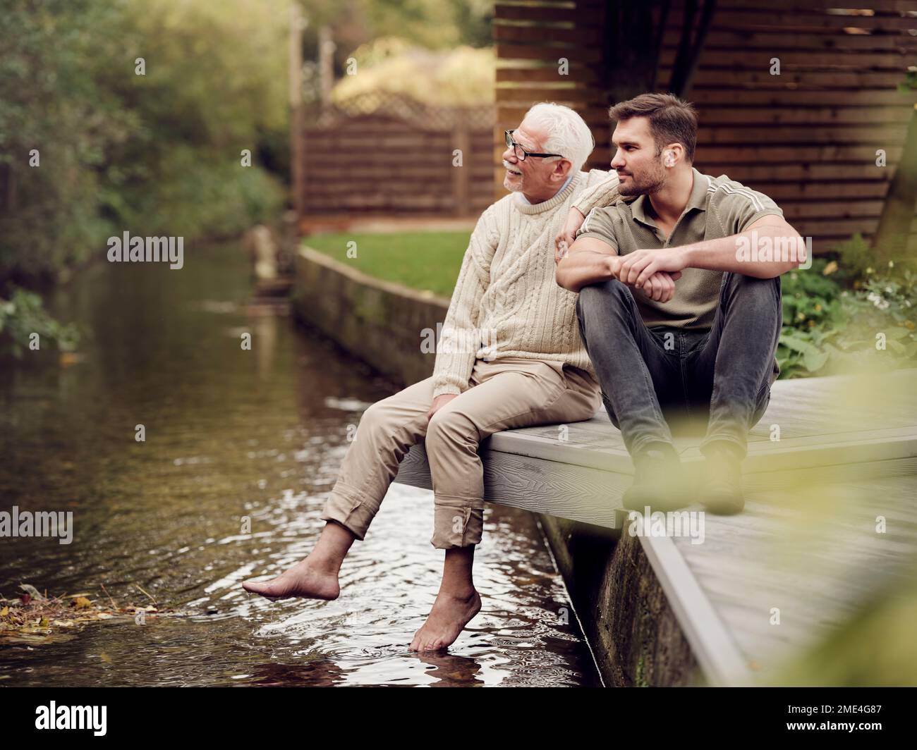 Adult son sitting with father in garden Stock Photo - Alamy