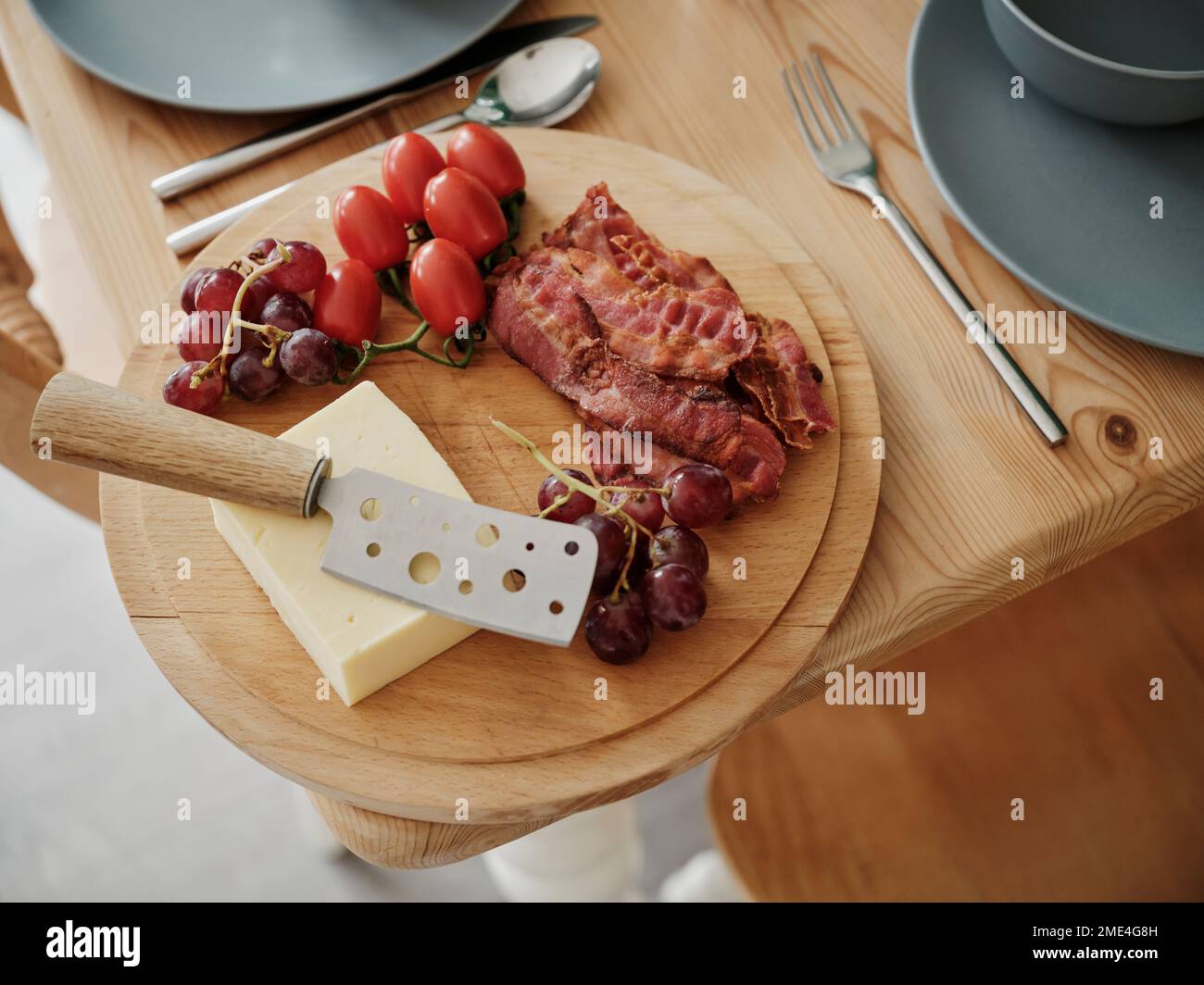 Cheese with tomatoes and grapes and bacon on kitchen table Stock Photo ...