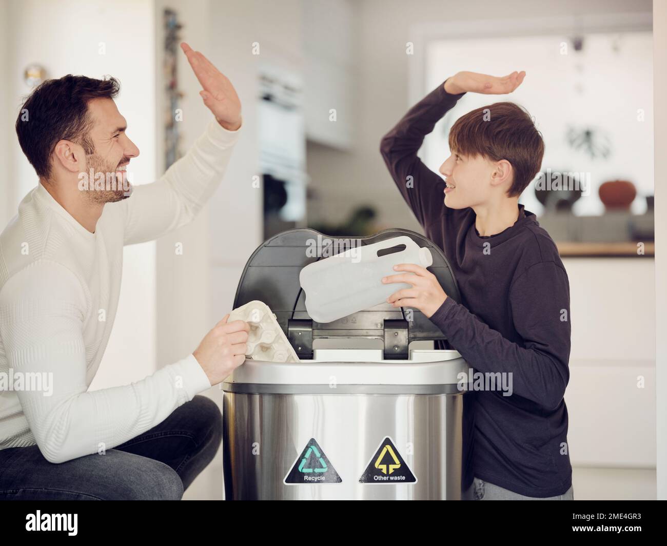 Father and son sorting waste paper and plastic into a sorting bin Stock ...
