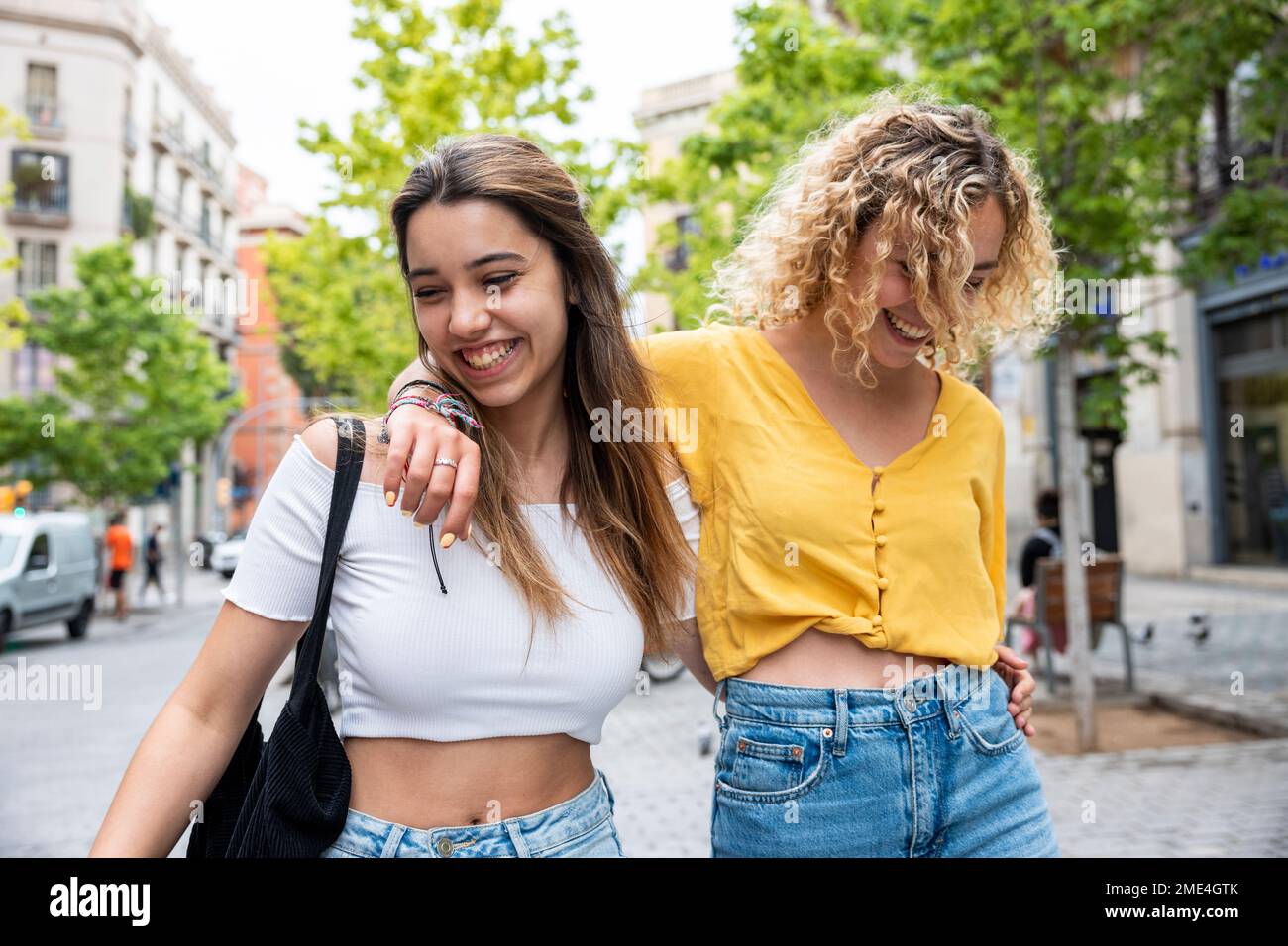 Happy young woman with friend walking on footpath Stock Photo - Alamy