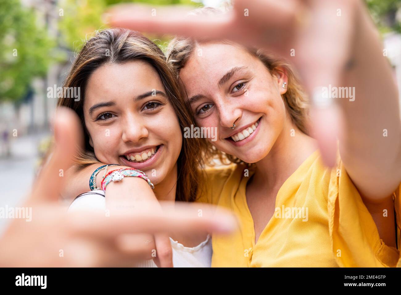 Happy young friends making finger frame Stock Photo - Alamy