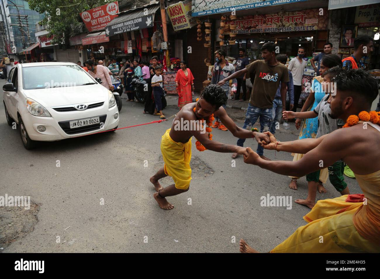 A devotee, with steel hooks pierced through his back, pulls a car ...