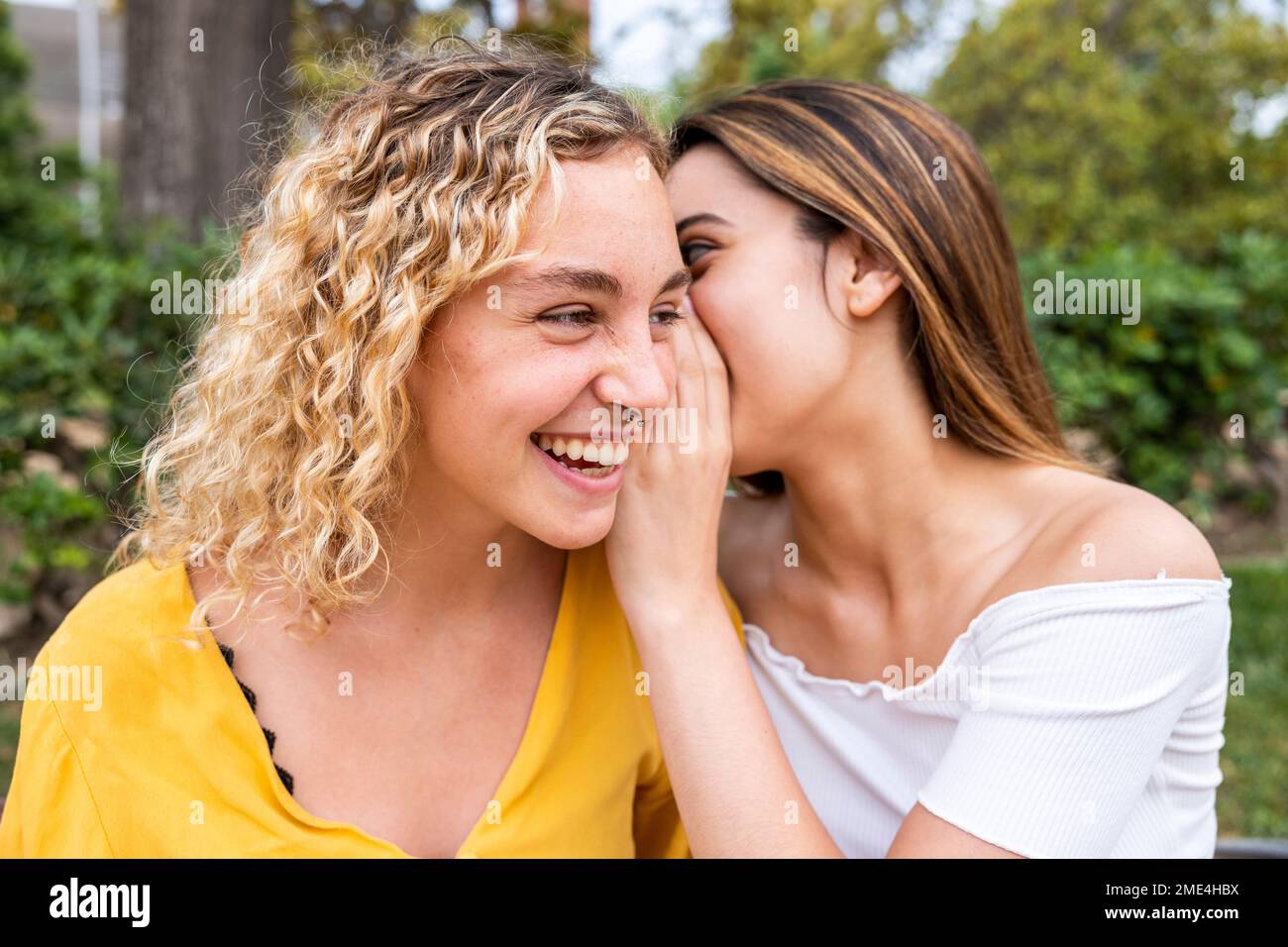 Women whispering in friends ear hi-res stock photography and images - Alamy