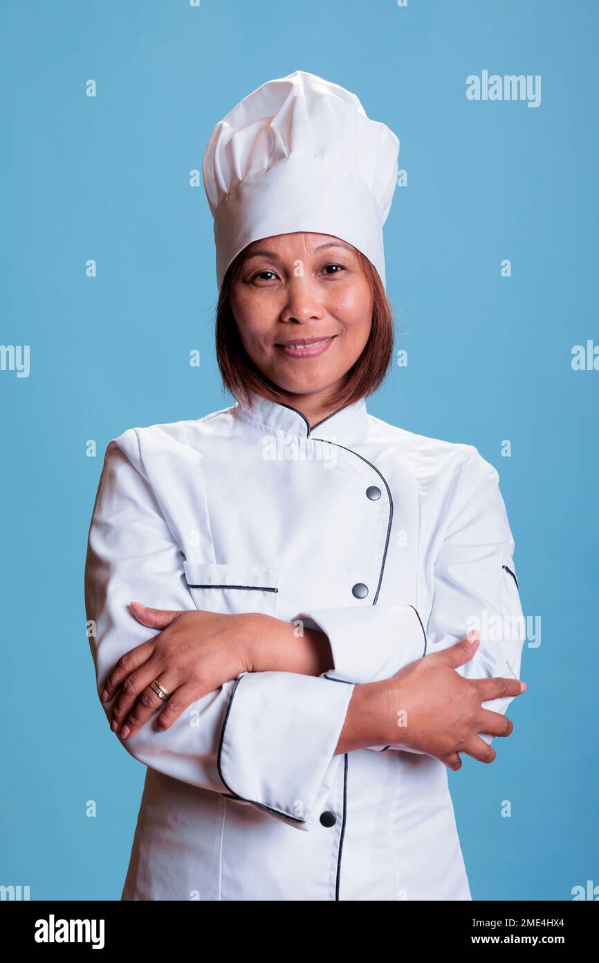 Smiling positive chef smiling at camera while preparing culinary meal ...