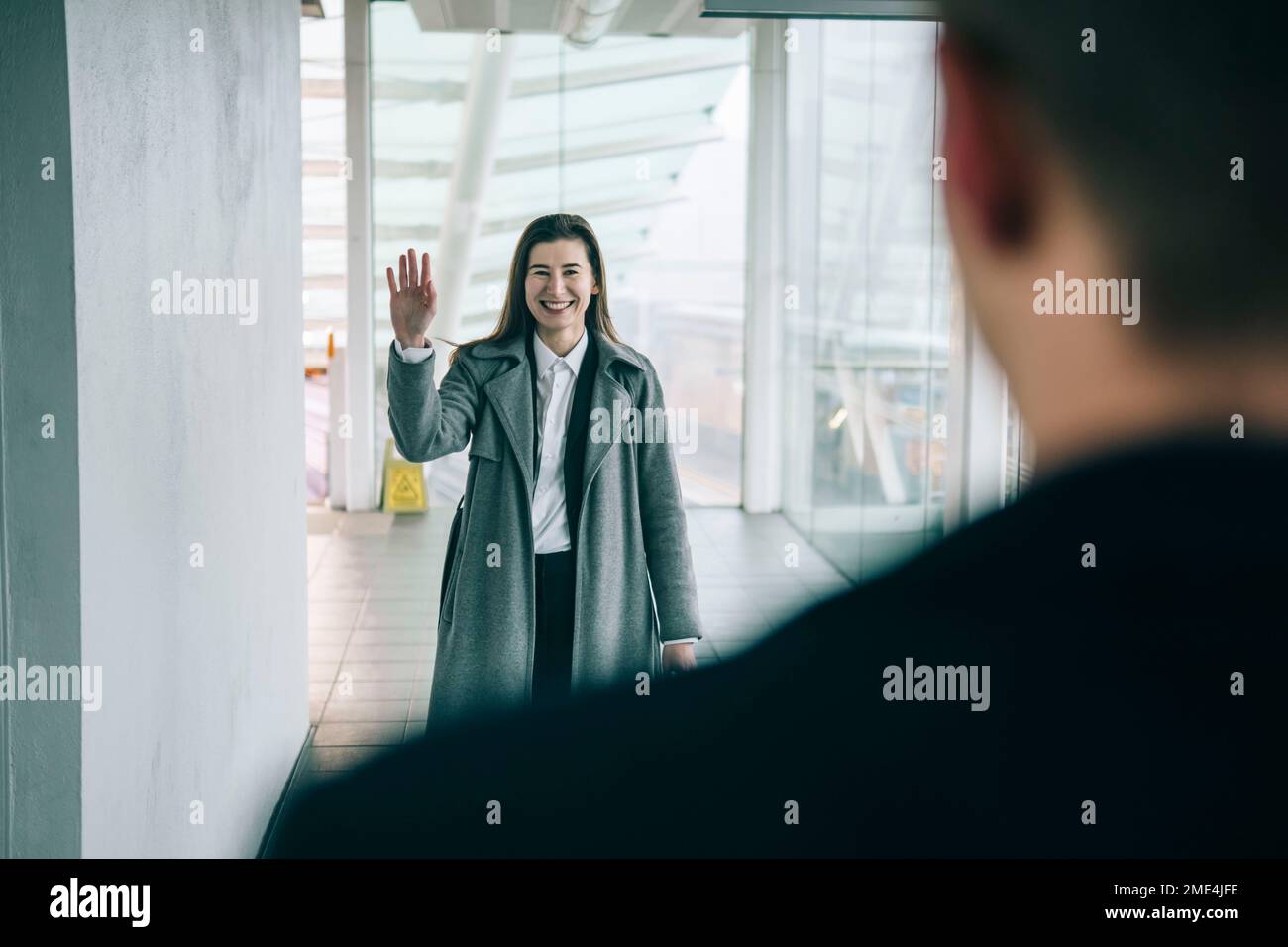 Happy businesswoman waving at colleague in railroad station Stock Photo ...