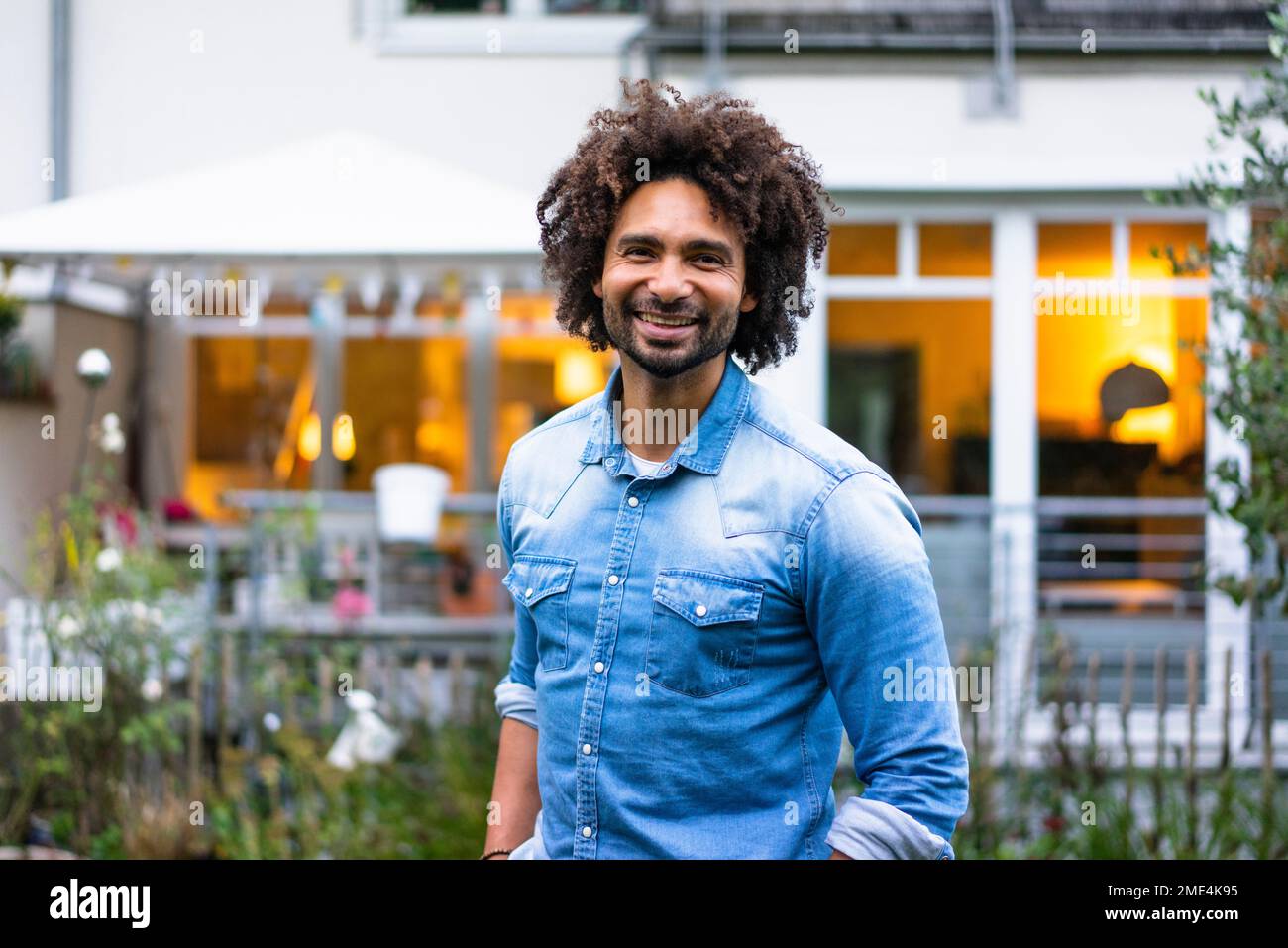 Happy man with afro hairstyle standing in front of house Stock Photo ...