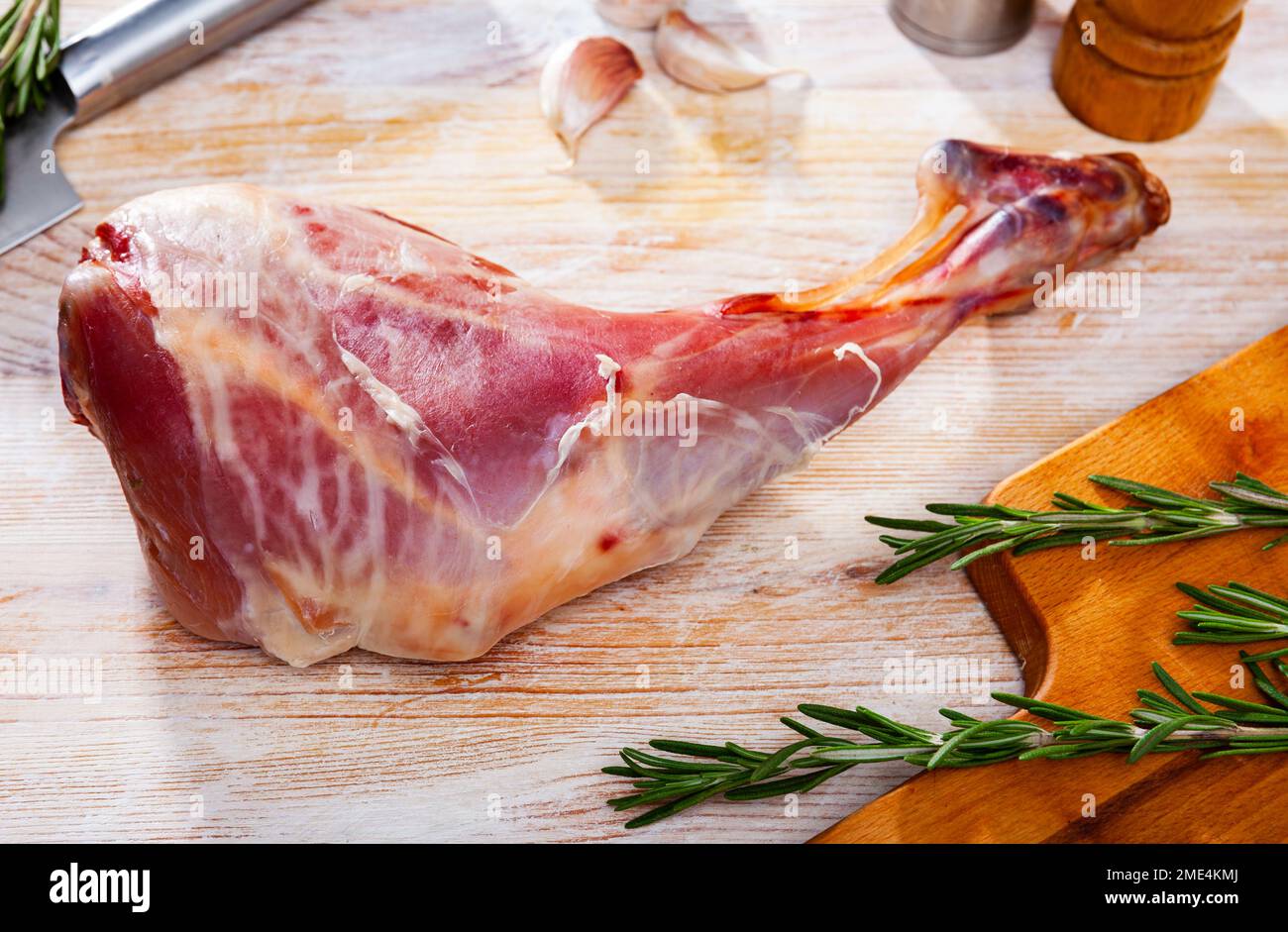Raw leg of milk-fed lamb with condiments Stock Photo - Alamy