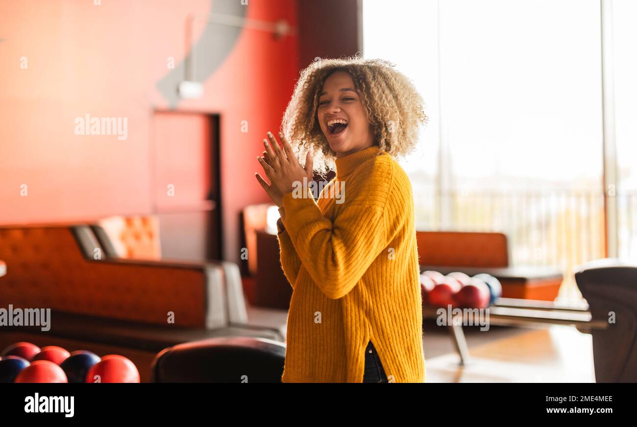Cheerful young woman clapping at bowling alley Stock Photo - Alamy