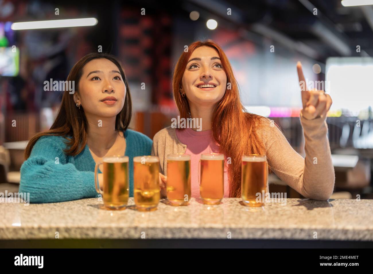 Happy woman pointing to friend with glasses of beer at counter Stock ...