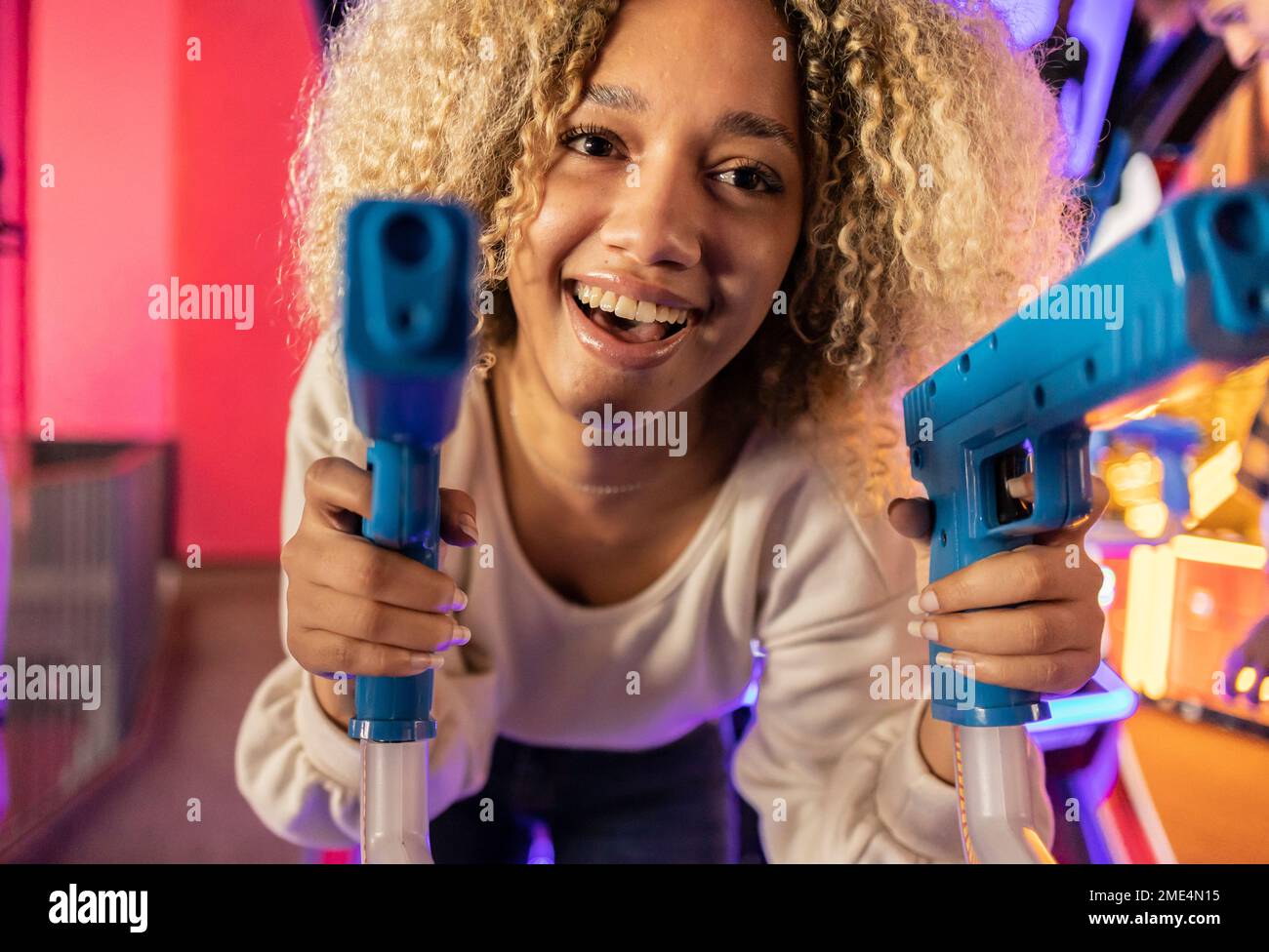 Happy young woman playing target shooting games at arcade Stock Photo ...