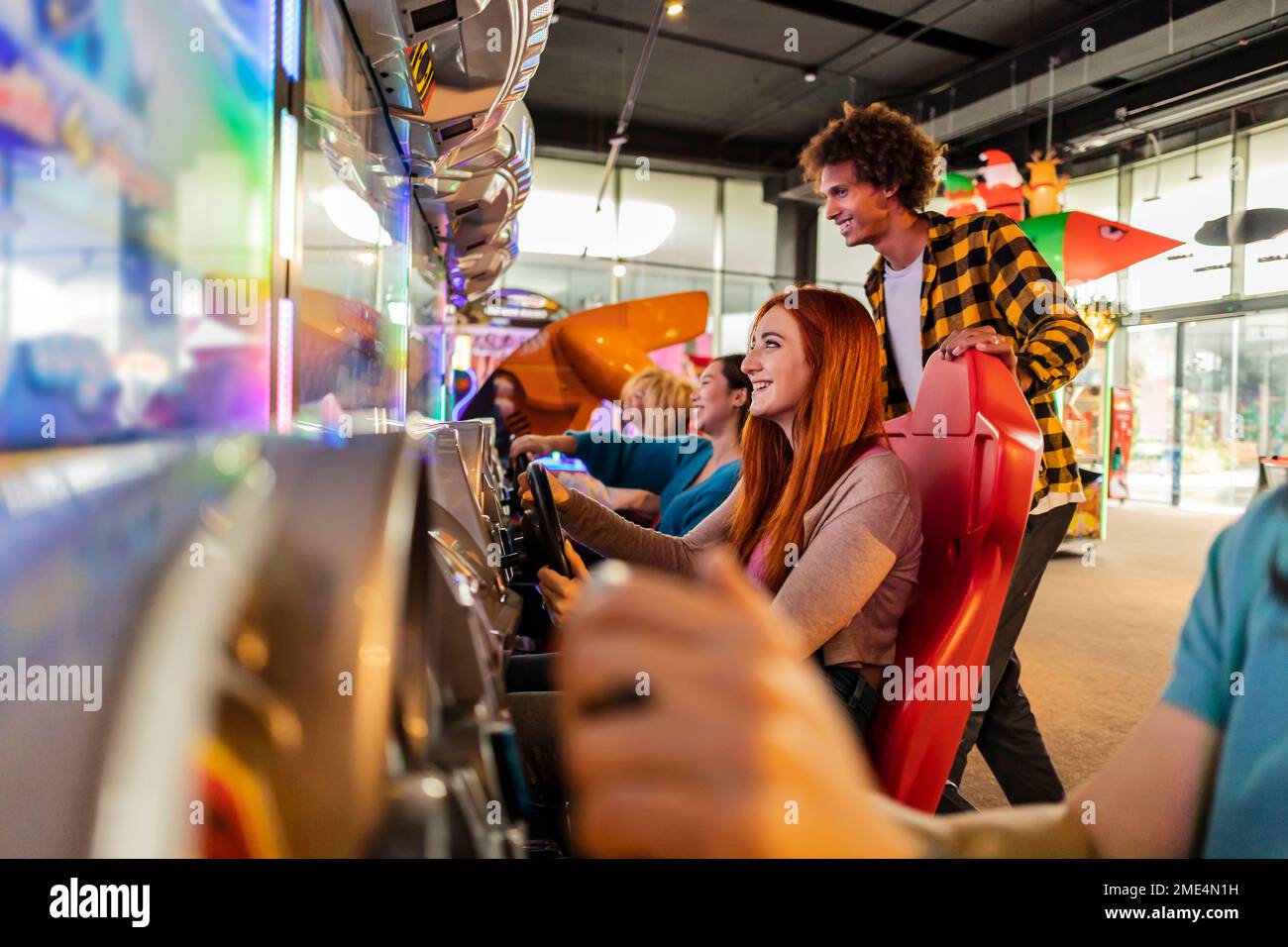 Happy friends having fun playing racing video game at arcade Stock ...