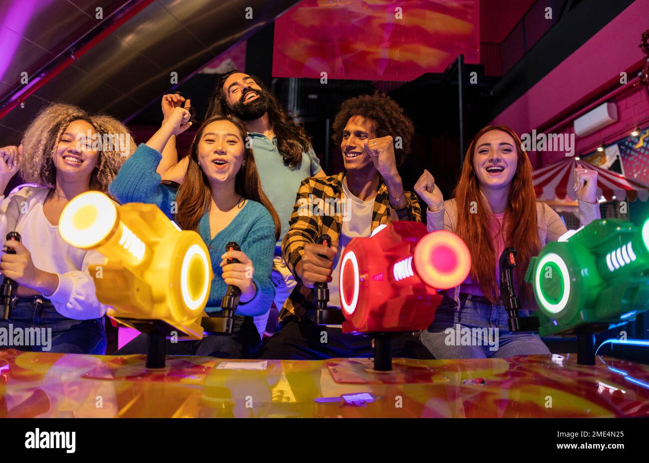 Excited multiracial friends playing in amusement arcade Stock Photo - Alamy
