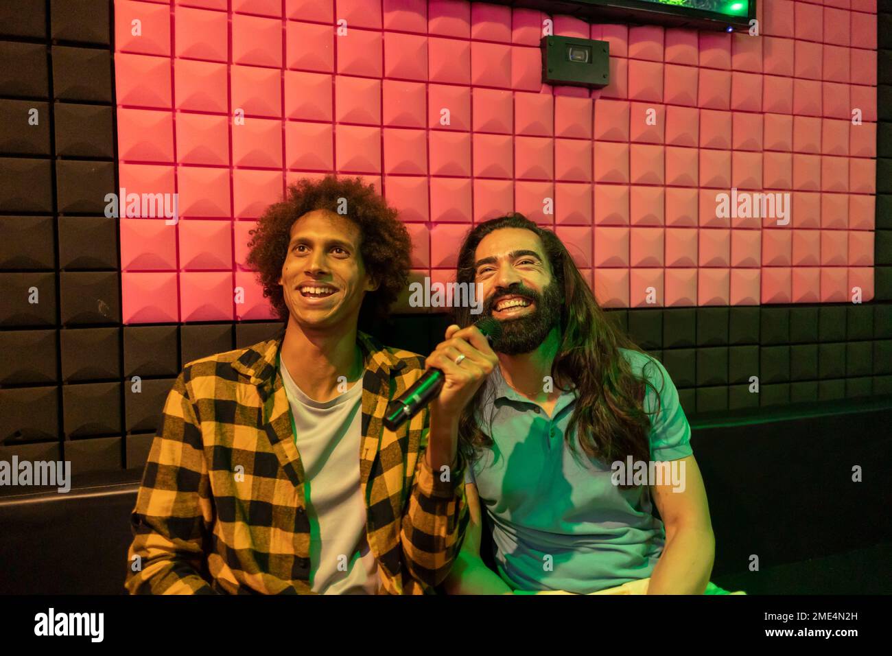 Happy men singing karaoke at amusement arcade Stock Photo - Alamy