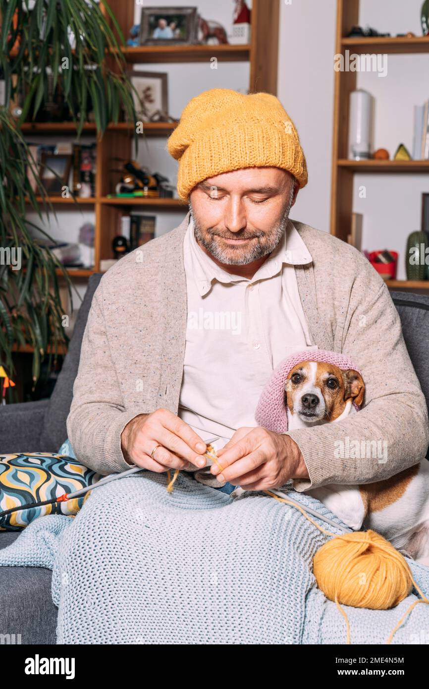 Man with dog knitting on couch at home Stock Photo - Alamy