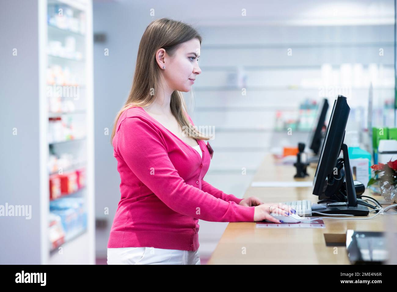 Pharmacist working on desktop PC at counter in pharmacy Stock Photo - Alamy
