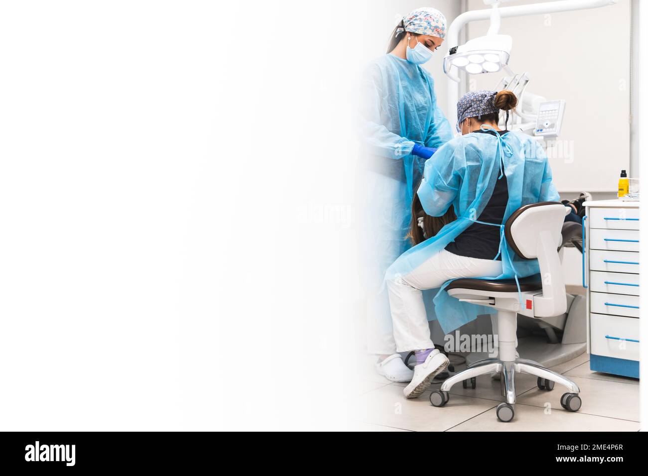 Dentist and assistant in operating gowns working at clinic Stock Photo ...