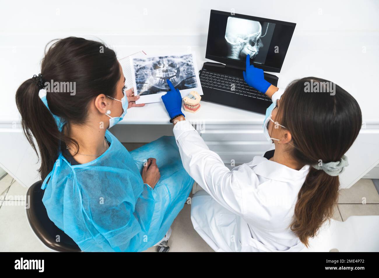 Young dentists discussing over x-ray image and using laptop at clinic ...