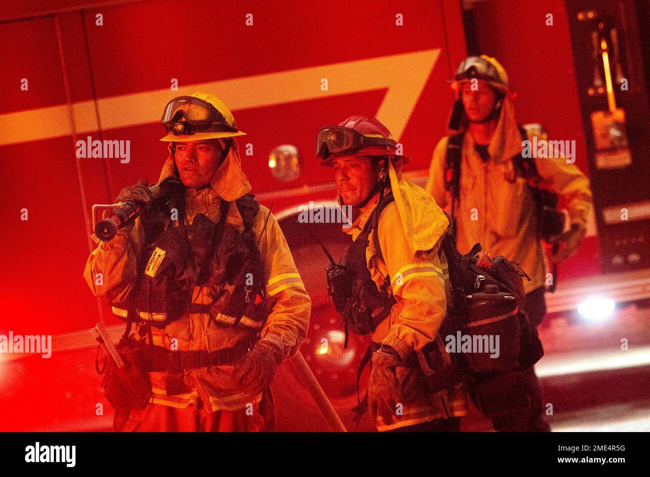 Firefighters watch flames burst from a propane tank as the Dixie Fire ...