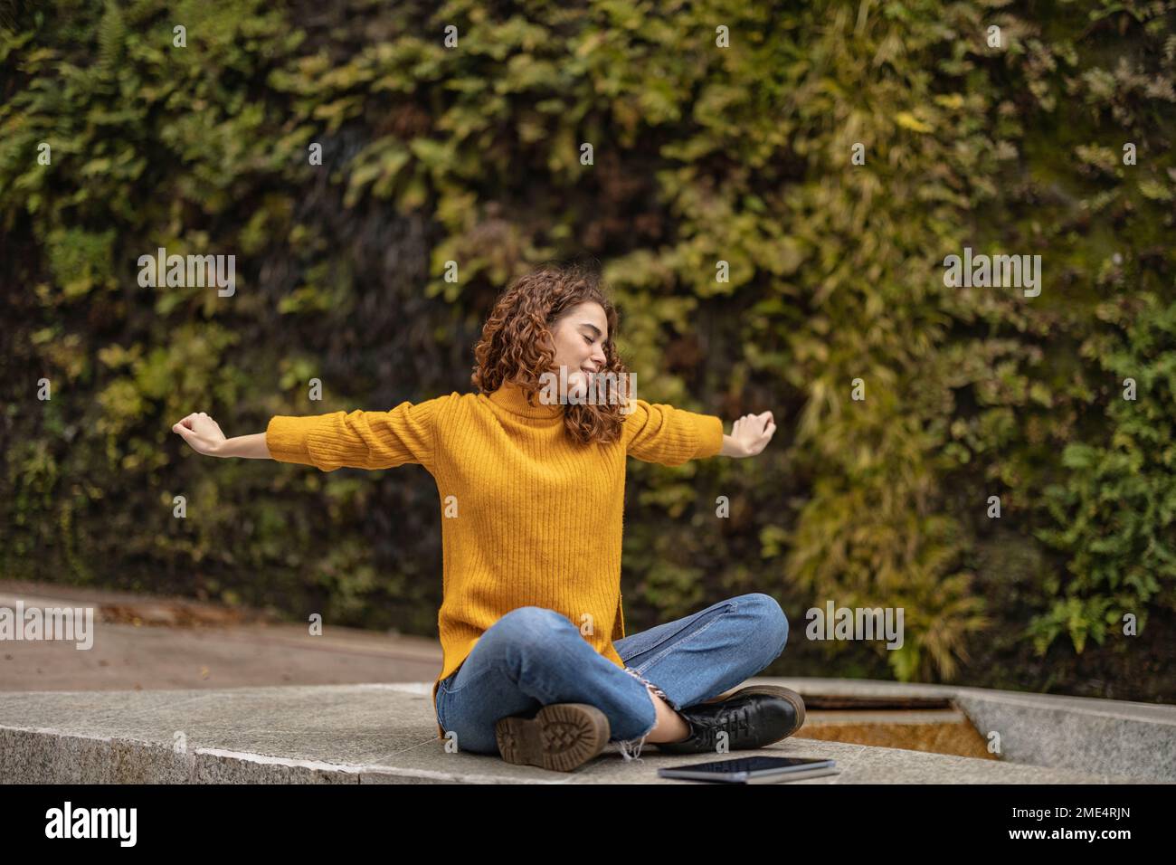 Smiling young woman stretching arms sitting on seat Stock Photo - Alamy