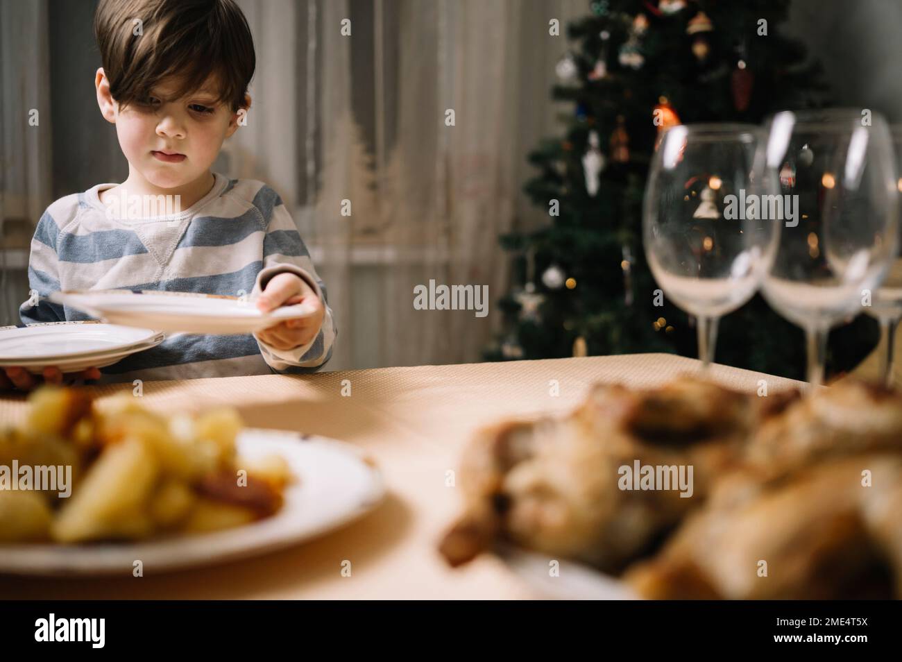 Cute boy arranging plates on dining table at home Stock Photo - Alamy