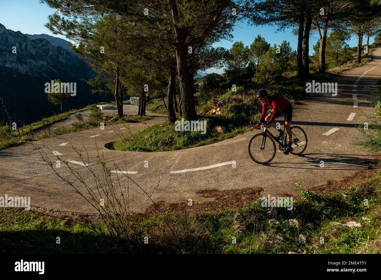 Mature cyclist riding cycle on winding road Stock Photo - Alamy