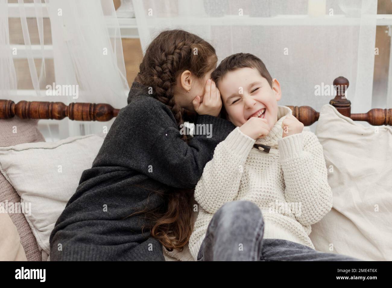 Sister whispering in brother's ear on sofa at home Stock Photo - Alamy