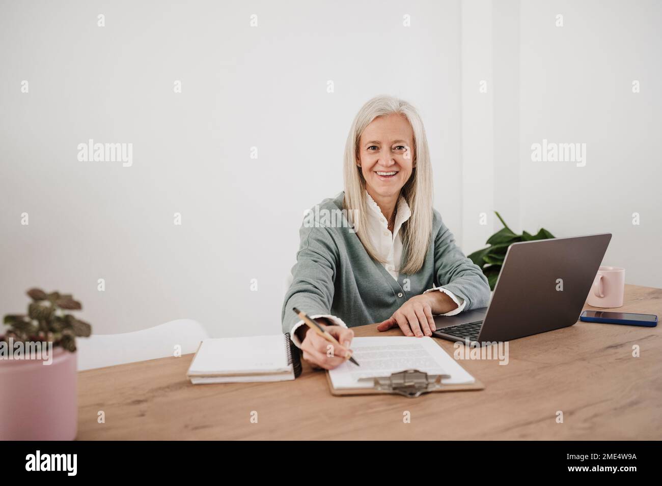 Happy freelancer with documents and laptop in home office Stock Photo ...