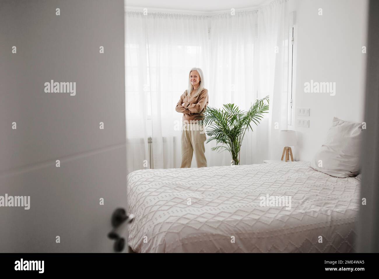 Mature woman with arms crossed standing in bedroom Stock Photo - Alamy
