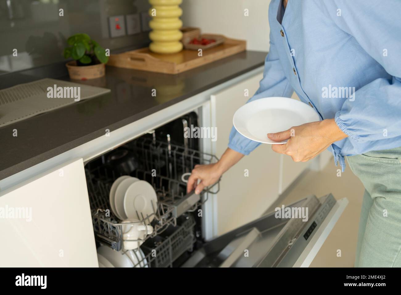 Hands of woman loading plates in dishwasher at home Stock Photo - Alamy