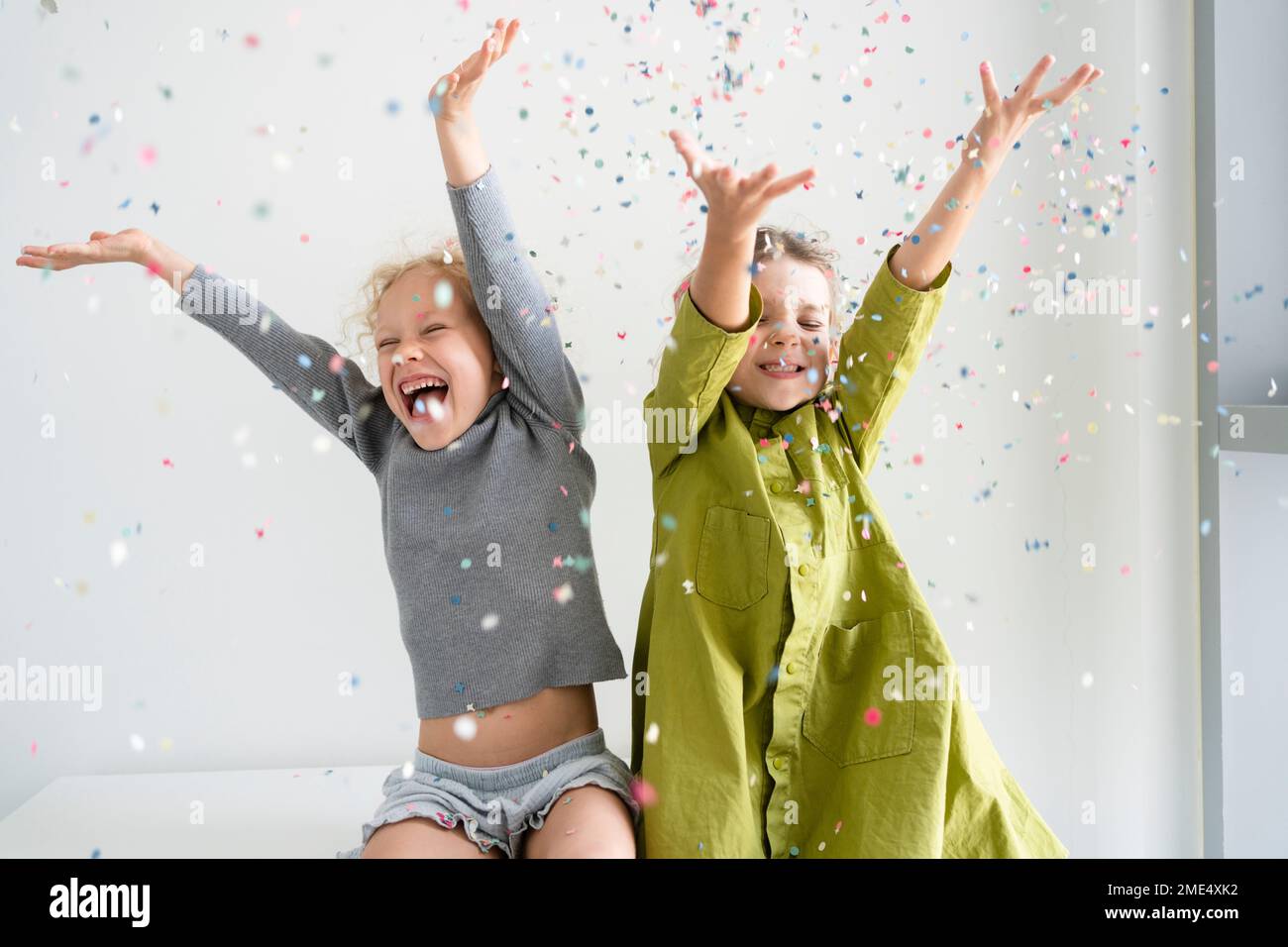 Girls having fun throwing confetti at home Stock Photo - Alamy
