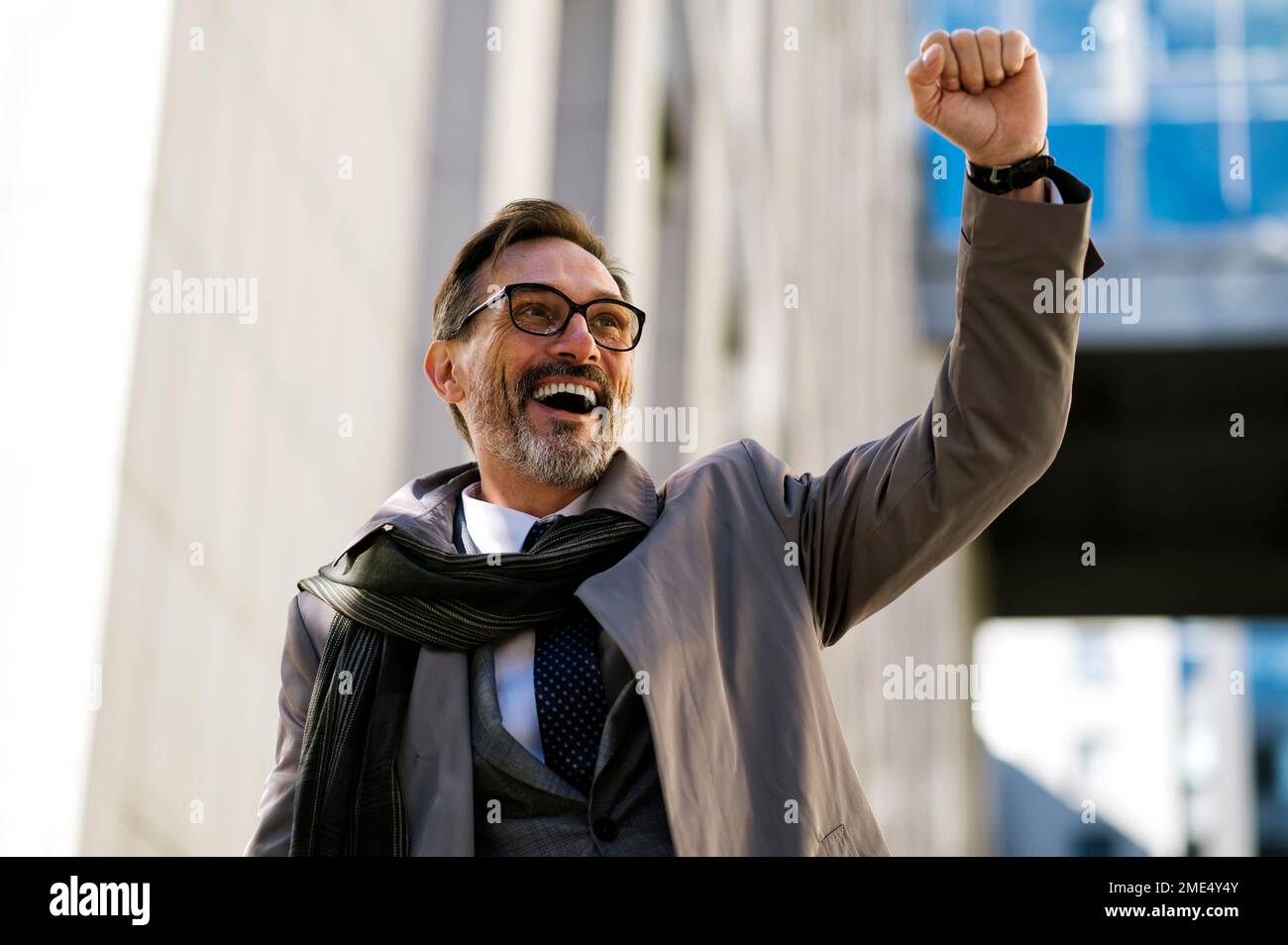 Happy businessman making fist outside building Stock Photo - Alamy