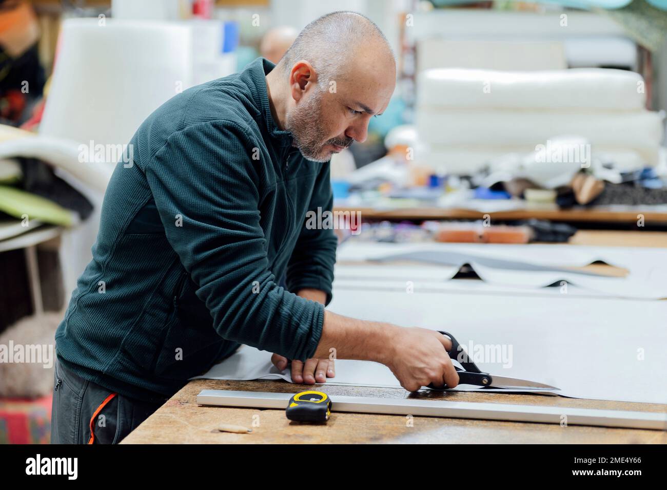 Craftsman cutting fabric at upholstery workshop Stock Photo - Alamy