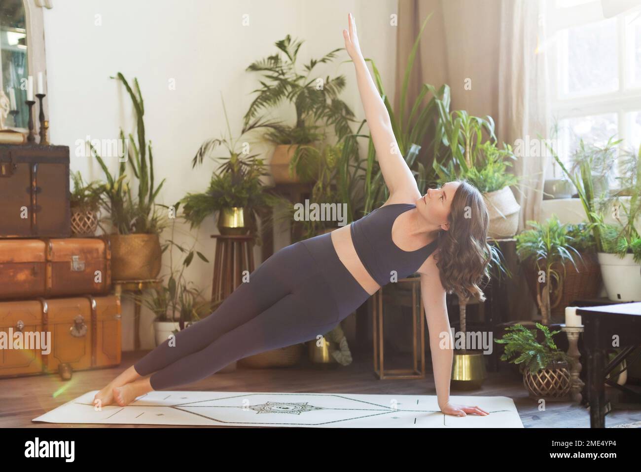 Woman practicing side plank pose on mat at home Stock Photo - Alamy