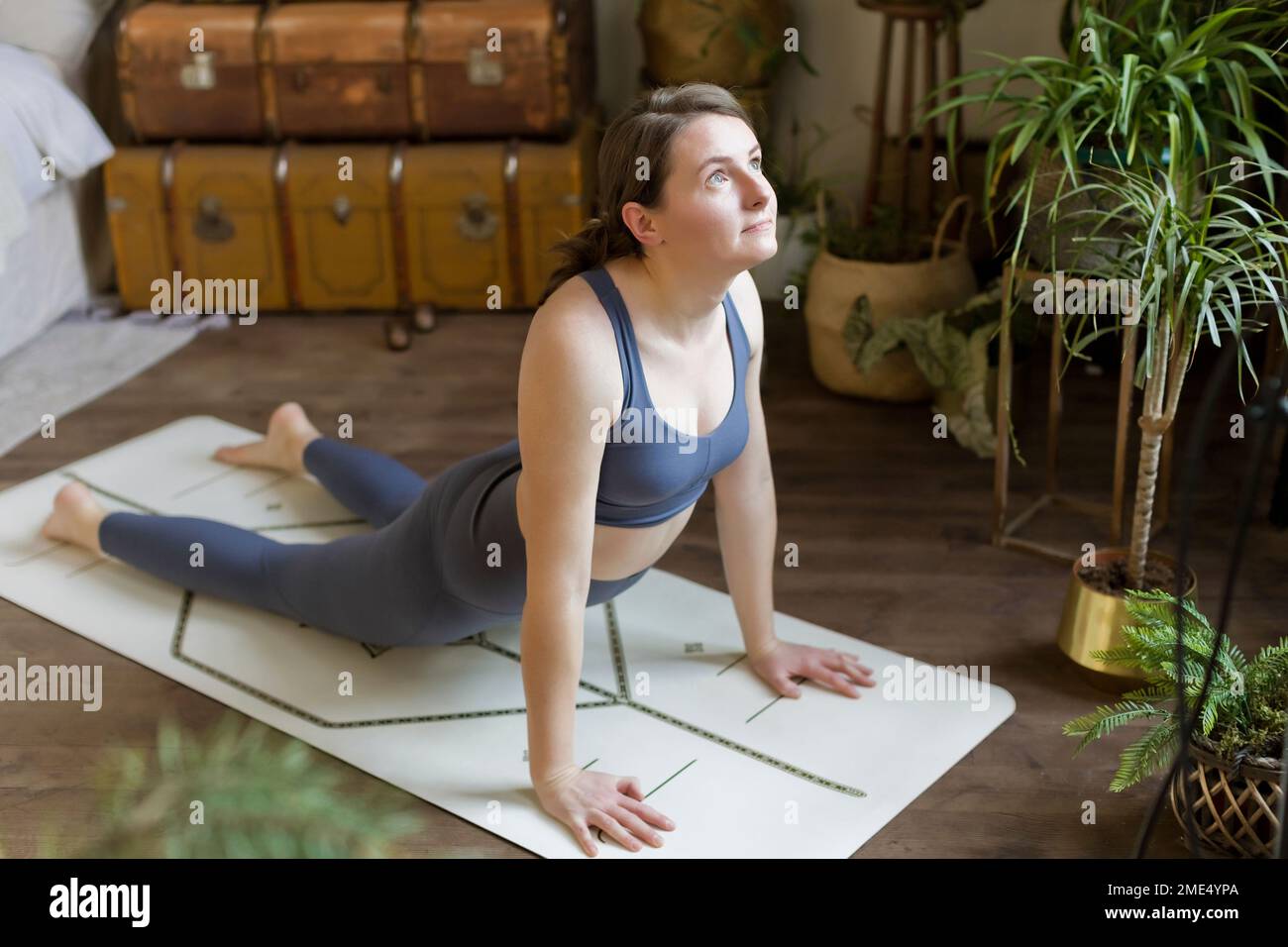 Woman practicing upward facing dog position on mat at home Stock Photo ...
